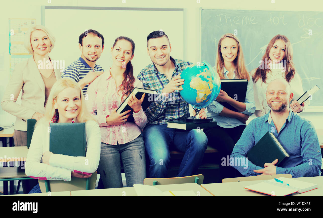 Portrait of friendly smiling teacher and happy students in classroom ...