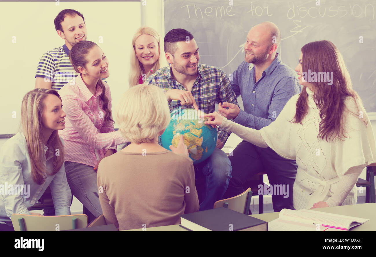 Highschool students having fun with a globe at geography class during a ...