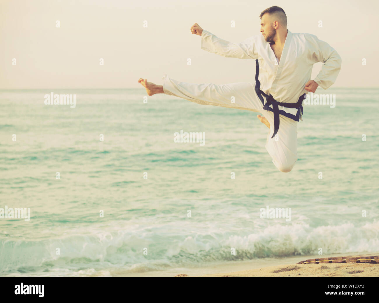 Active guy doing karate poses at sunset sea shore Stock Photo - Alamy