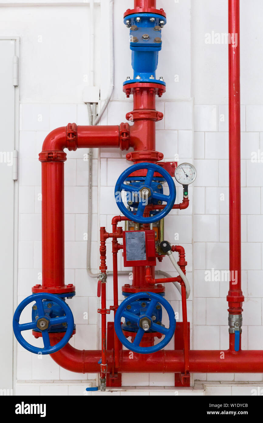 Red pipeline with blue control valves and manometer of water system ...