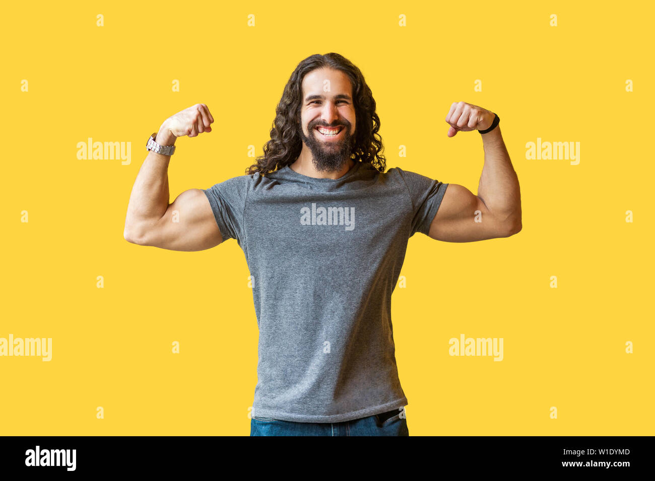 Portrait of happy strong bearded young bodybuilder man with long curly ...
