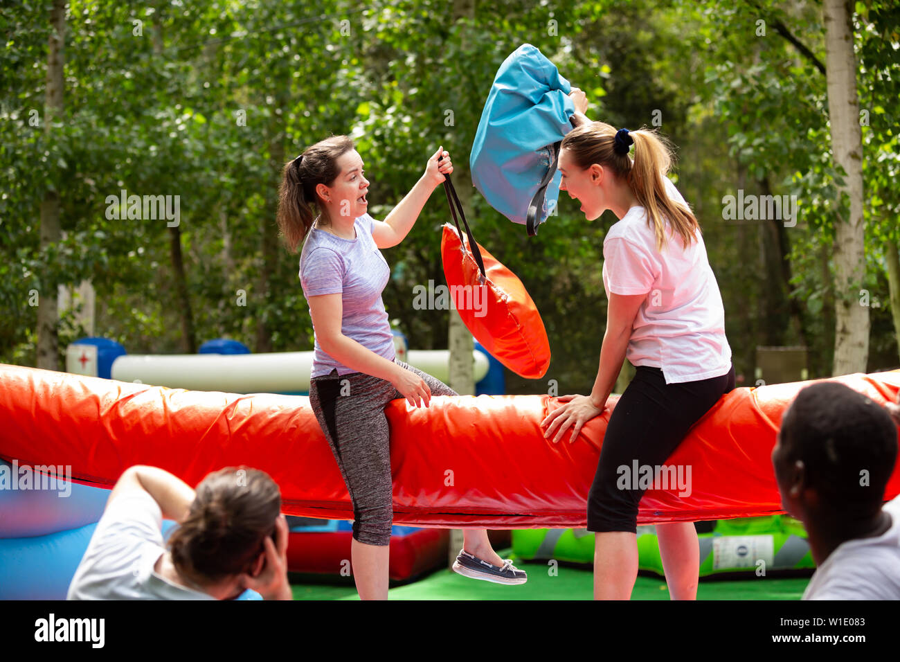 Cheerful girlfriends fighting with inflatable pillows in an amusement ...