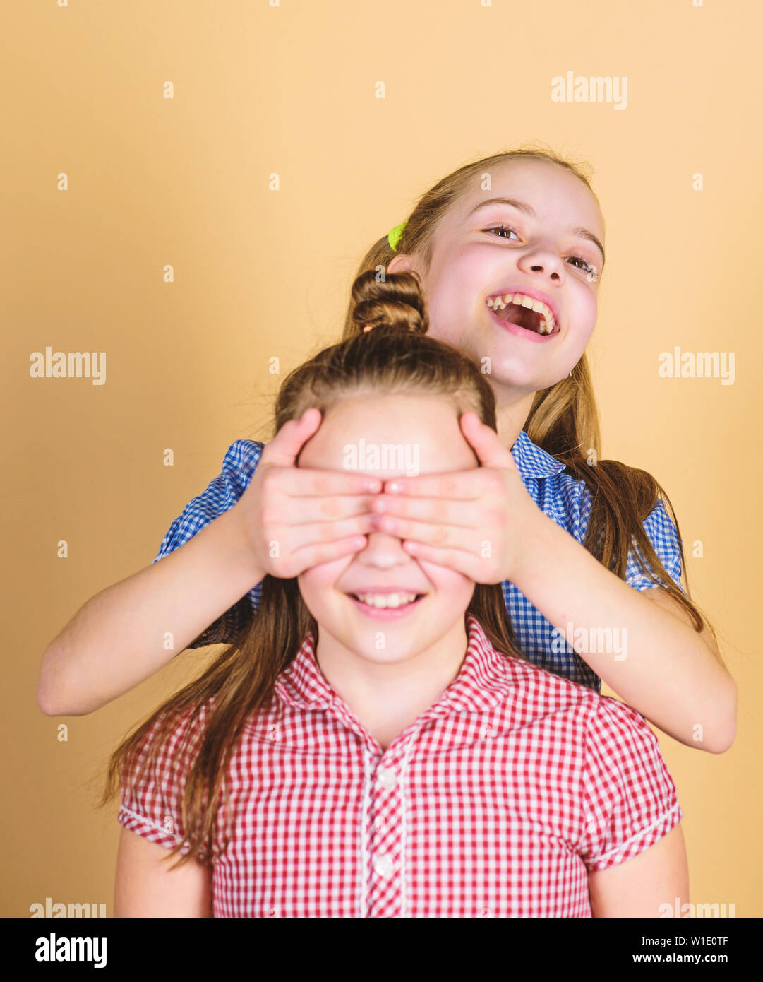 Guess who. Playful little girl covering eyes of her cheerful sister and ...
