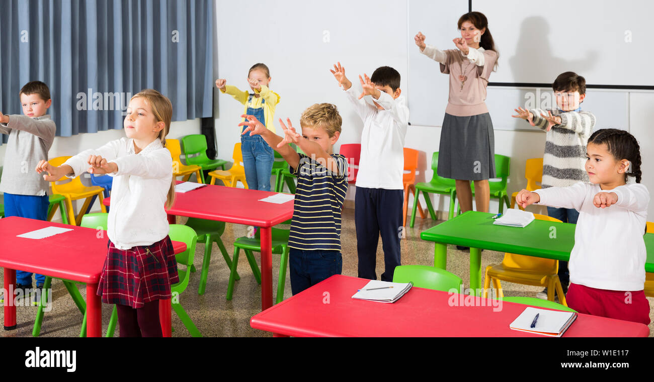 Portrait of schoolchildren with teacher performing daily physical ...