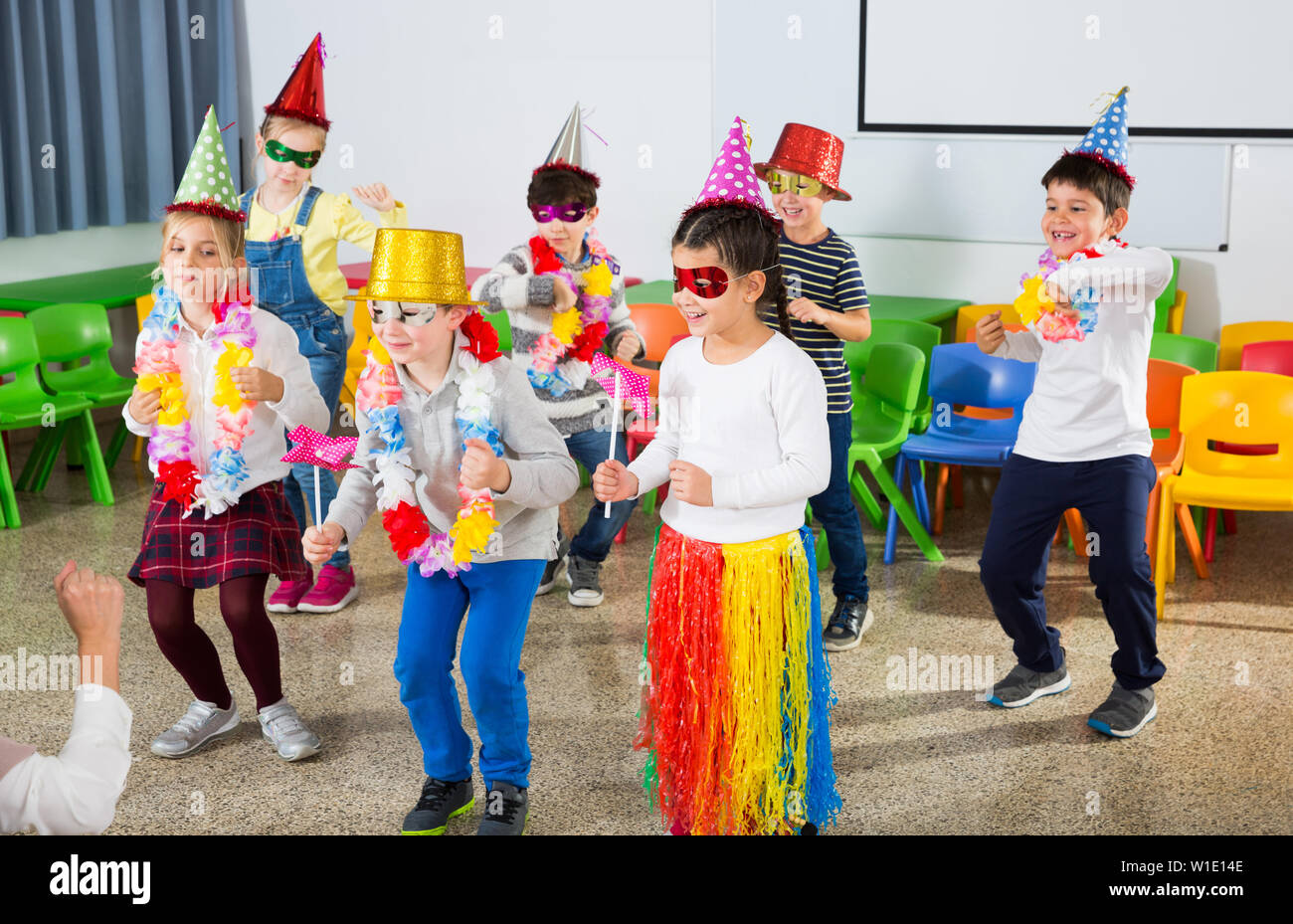 Group of cheerful school kids wearing festive hats having fun with ...