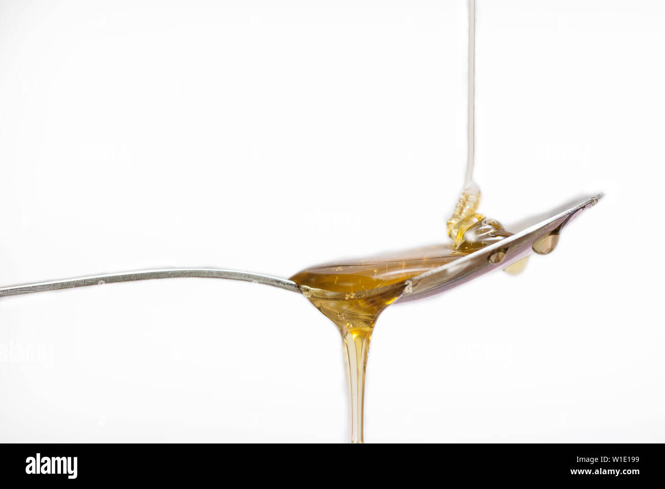 Honey dripping from a silver spoon on isolated white background Stock ...