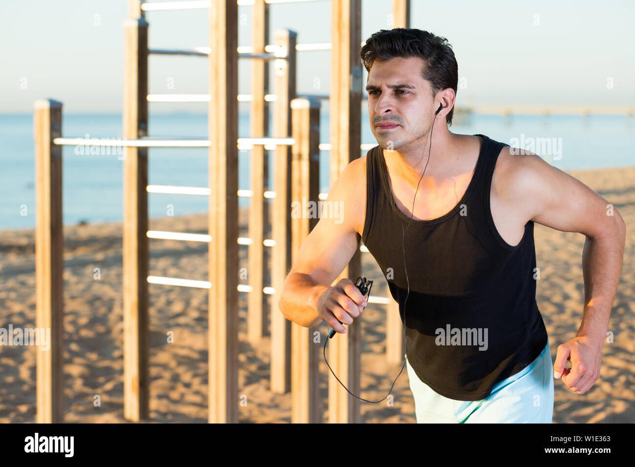 Serious strong man jogging during outdoor workout on beach Stock Photo ...