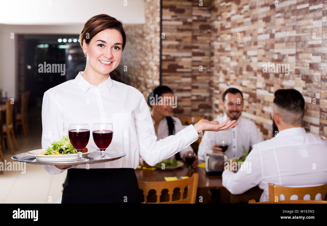 Positive female waiter welcoming guests to country restaurant Stock ...
