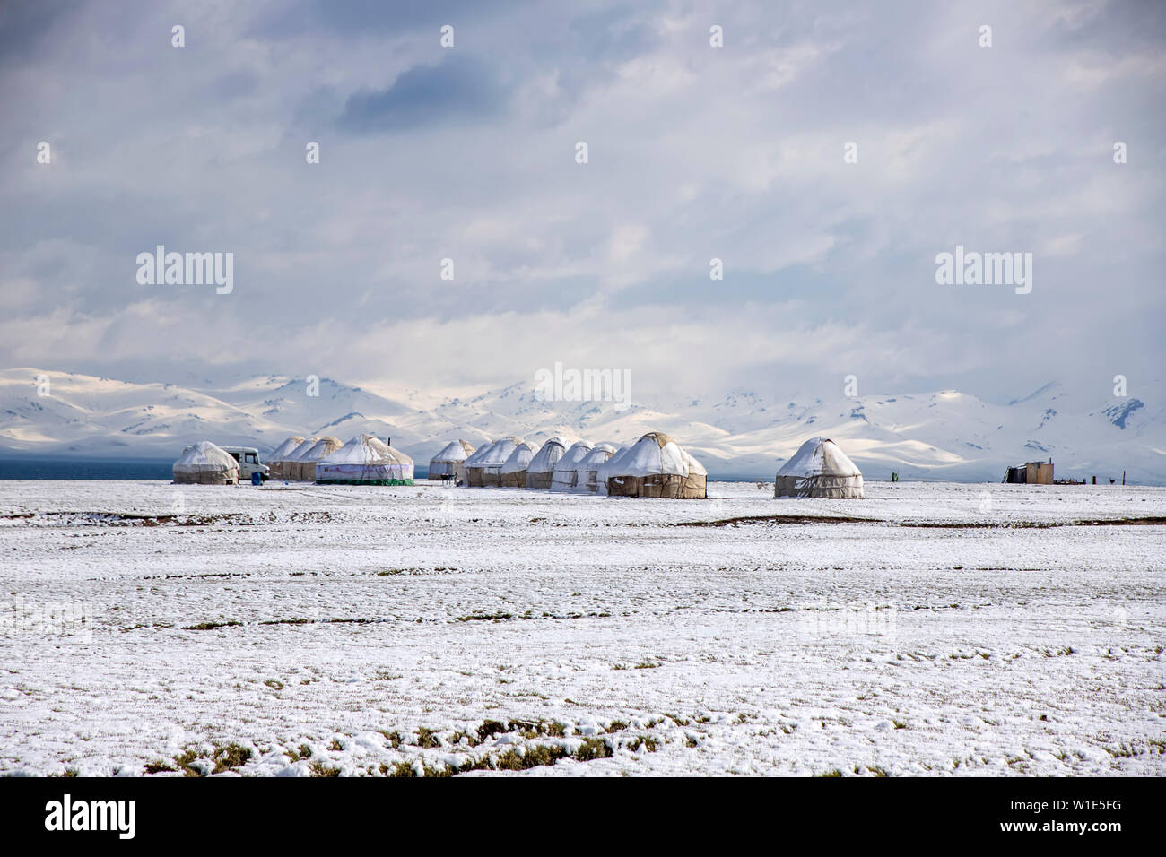 Yurt town on a snowy pasture on the background of snow-capped mountains ...