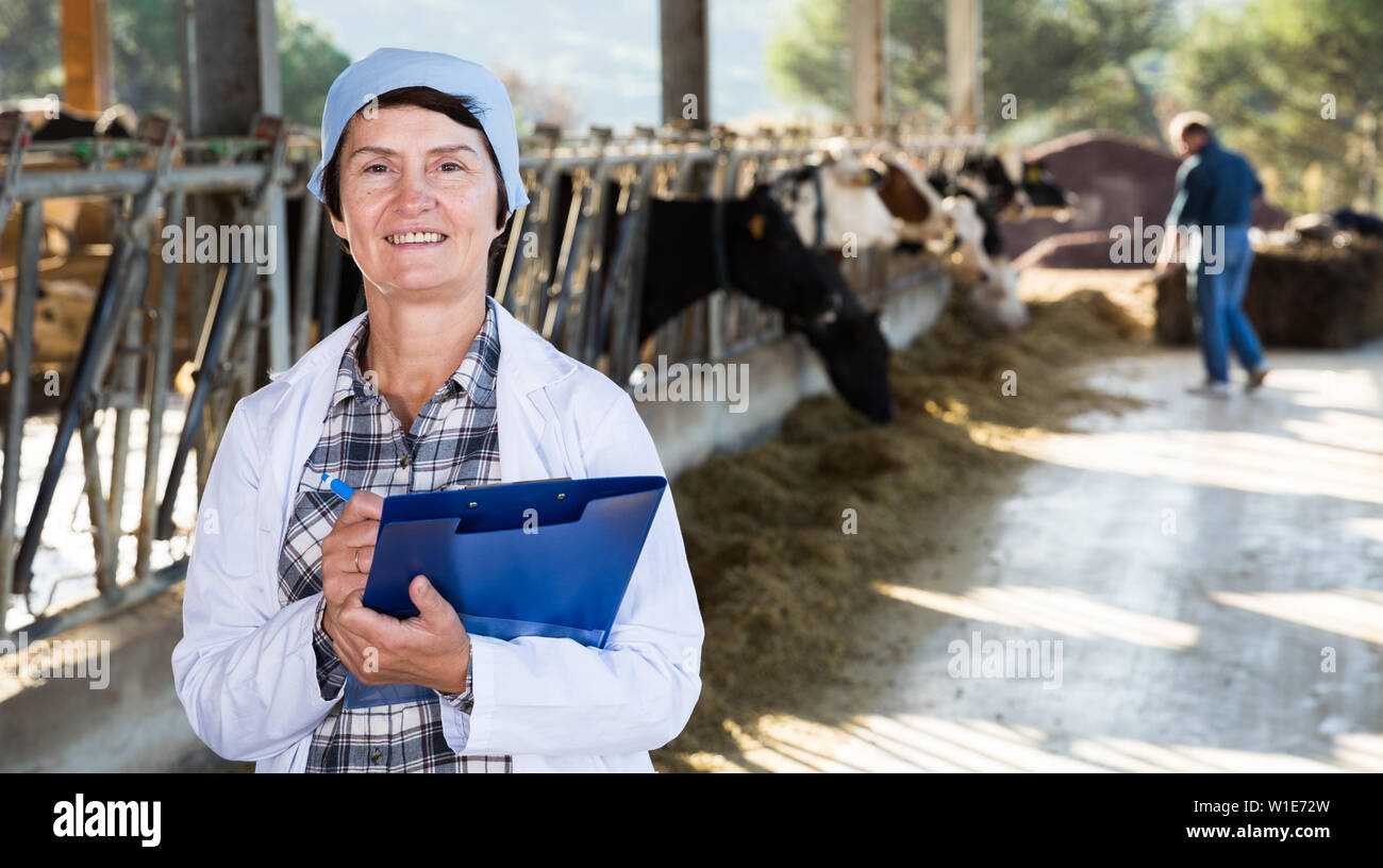 Female quality expert is standing in uniform at the cow farm Stock ...