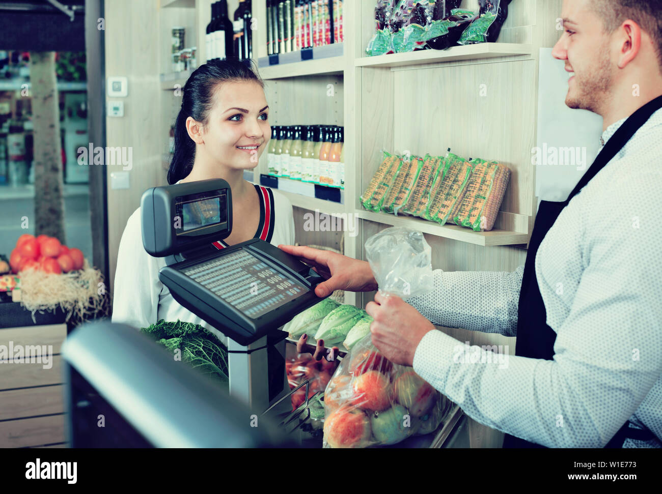 Male shopping assistant helping customer to weigh a purchases in ...