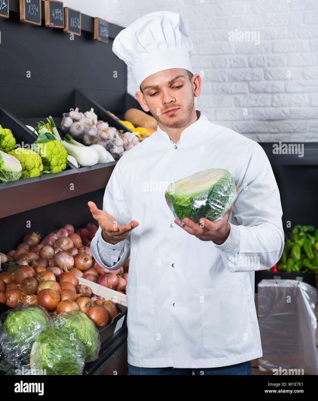 Satisfied pleasant male cook choosing vegetables in grocery shop Stock ...