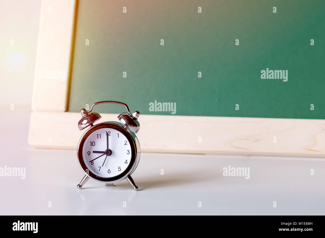 Back to school. Alarm clock on the background of the school board ...