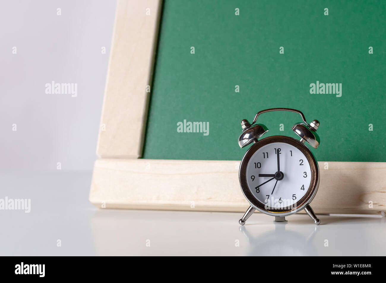 Back to school. Alarm clock on the background of the school board ...