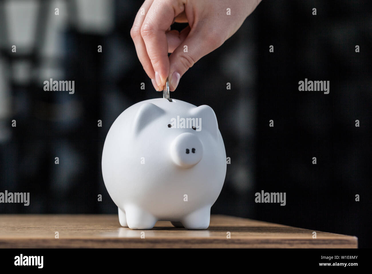 Inserting a coin into a piggy bank Stock Photo - Alamy