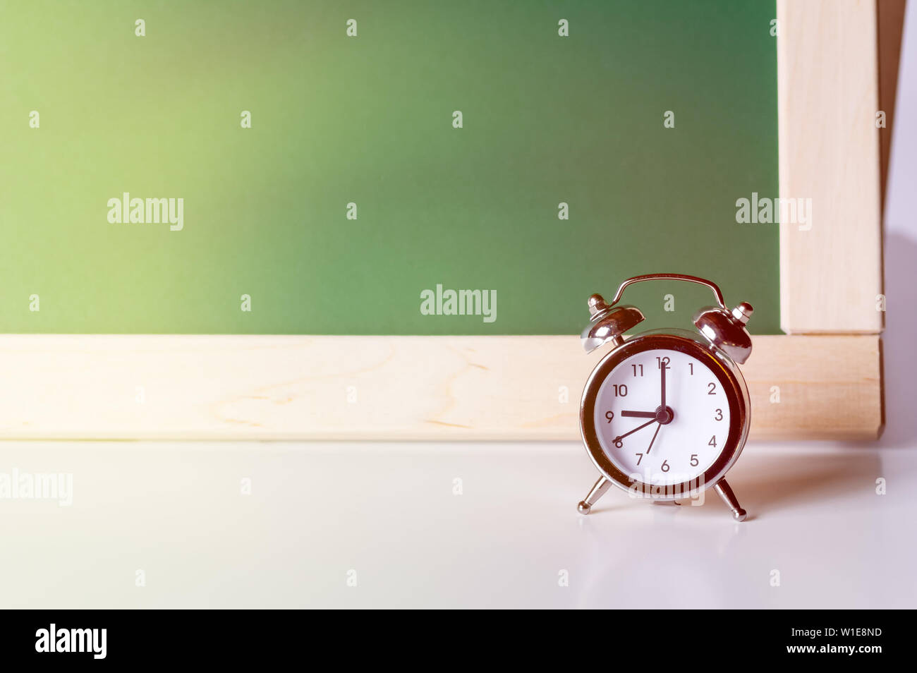 Back to school. Alarm clock on the background of the school board ...