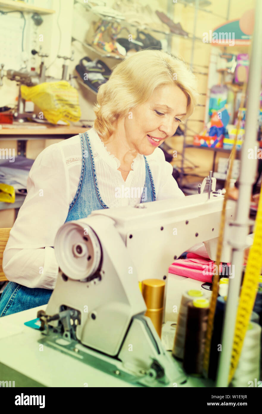 Portrait of professional female tailor working on sewing machine at a ...