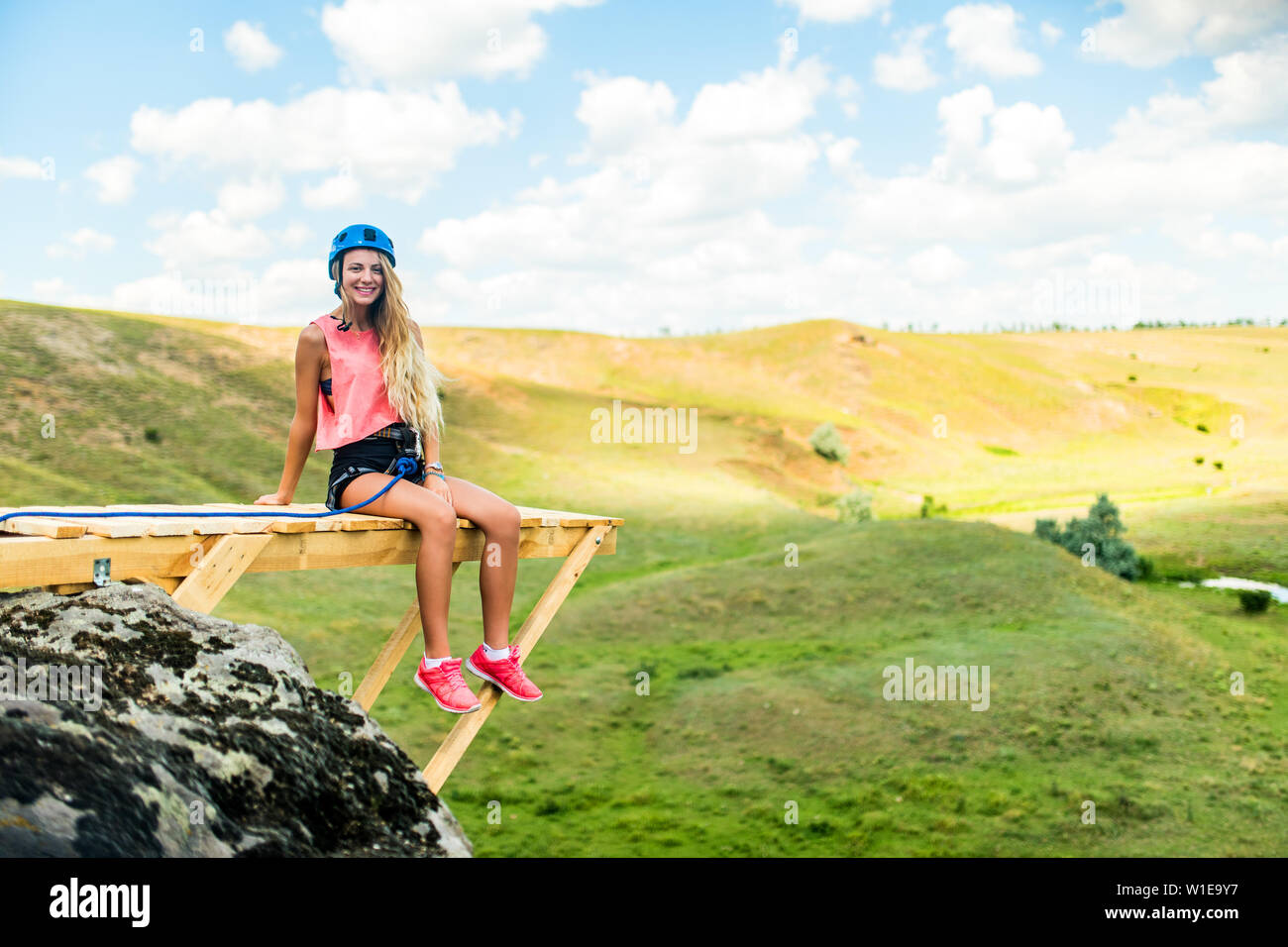 Woman sitting on a wooden ledge on a high mountain and view of the ...