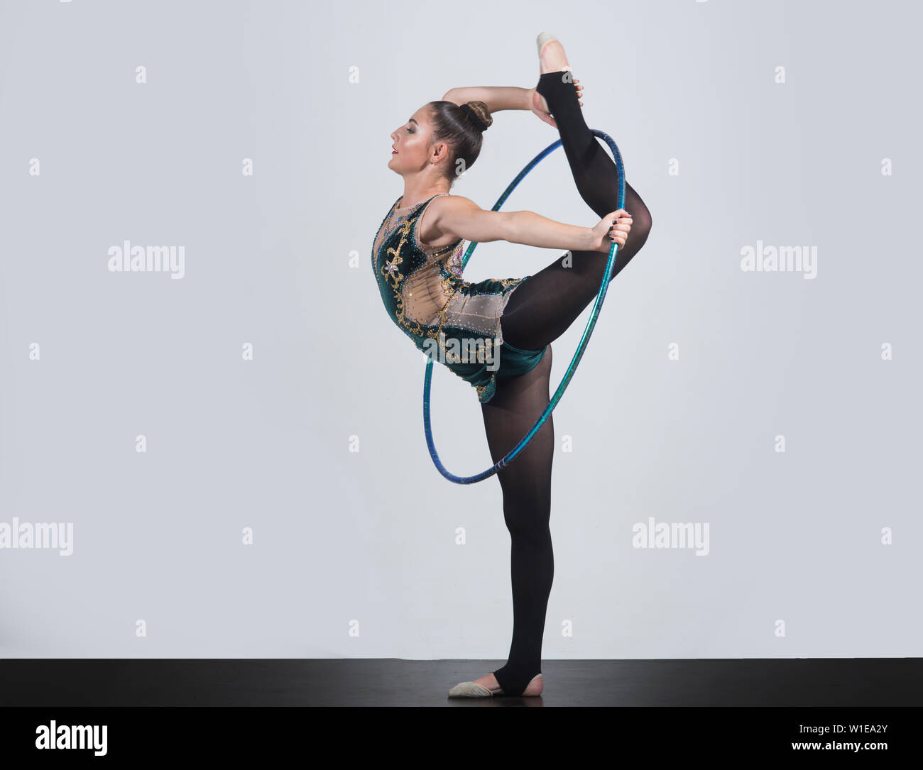 flexible girl playing hula hoop on grey background Stock Photo - Alamy