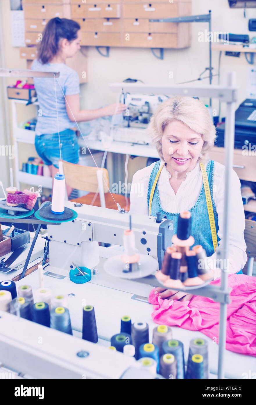 Portrait of two professional skilled female tailors working at a sewing ...
