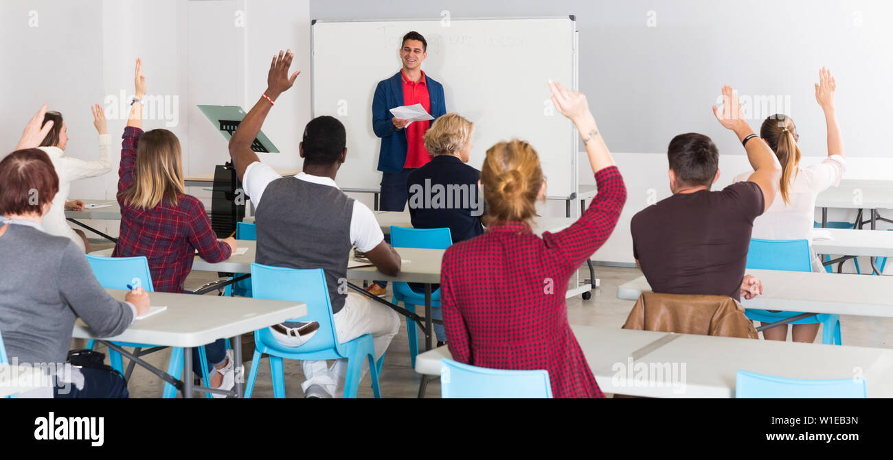Confident male student answering at whiteboard in front group of ...