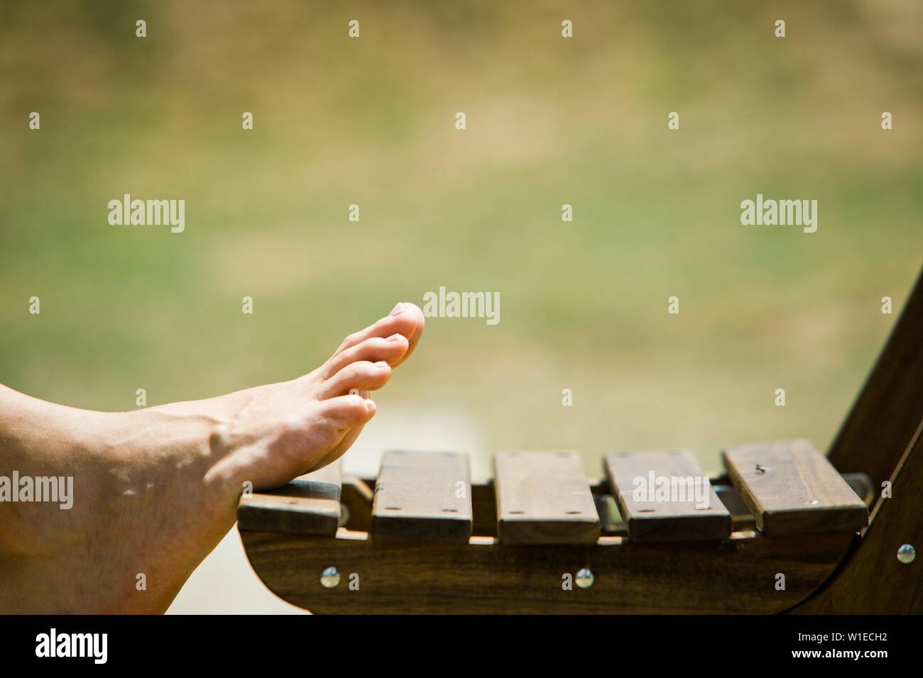 Woman's foot on wooden chair outdoor, toes detail Stock Photo - Alamy