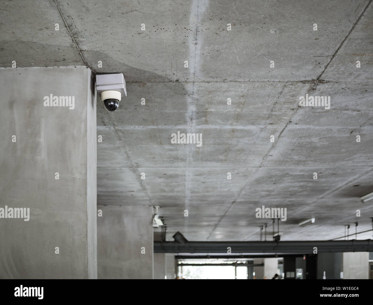CCTV camera installed on concrete ceiling in the parking lot with copy ...