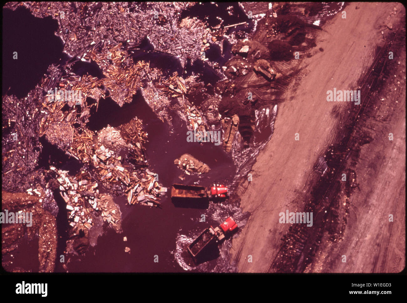 HUGE DUMP TRUCKS ARE THE RED SPOTS IN THIS AERIAL OF A SCRAP IRON YARD ...