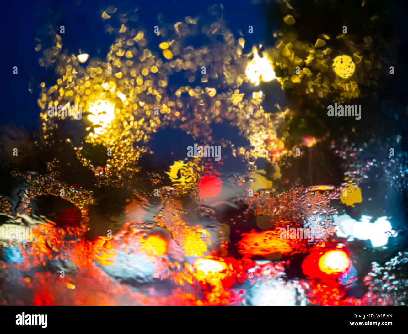 Blurred rain drops on car window with road light bokeh on rainy season ...