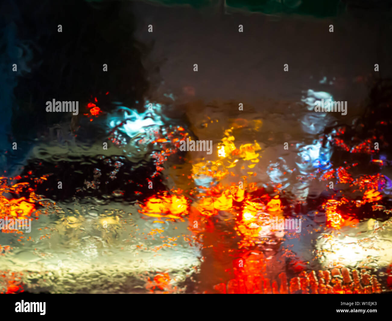 Blurred rain drops on car window with road light bokeh on rainy season ...