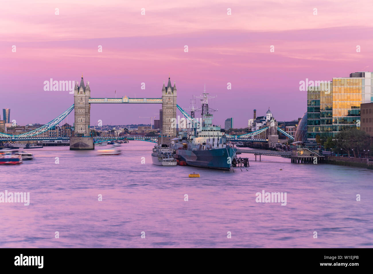 Tower Bridge with HMS Belfast at sunset with purple sky above the River ...