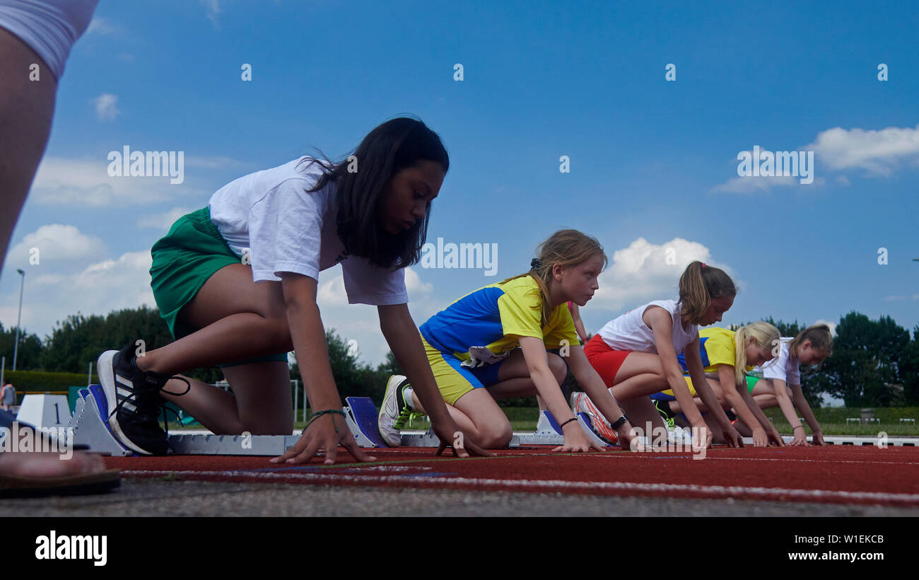 Girls preparing themselves at the starting blocks at an athletics track ...