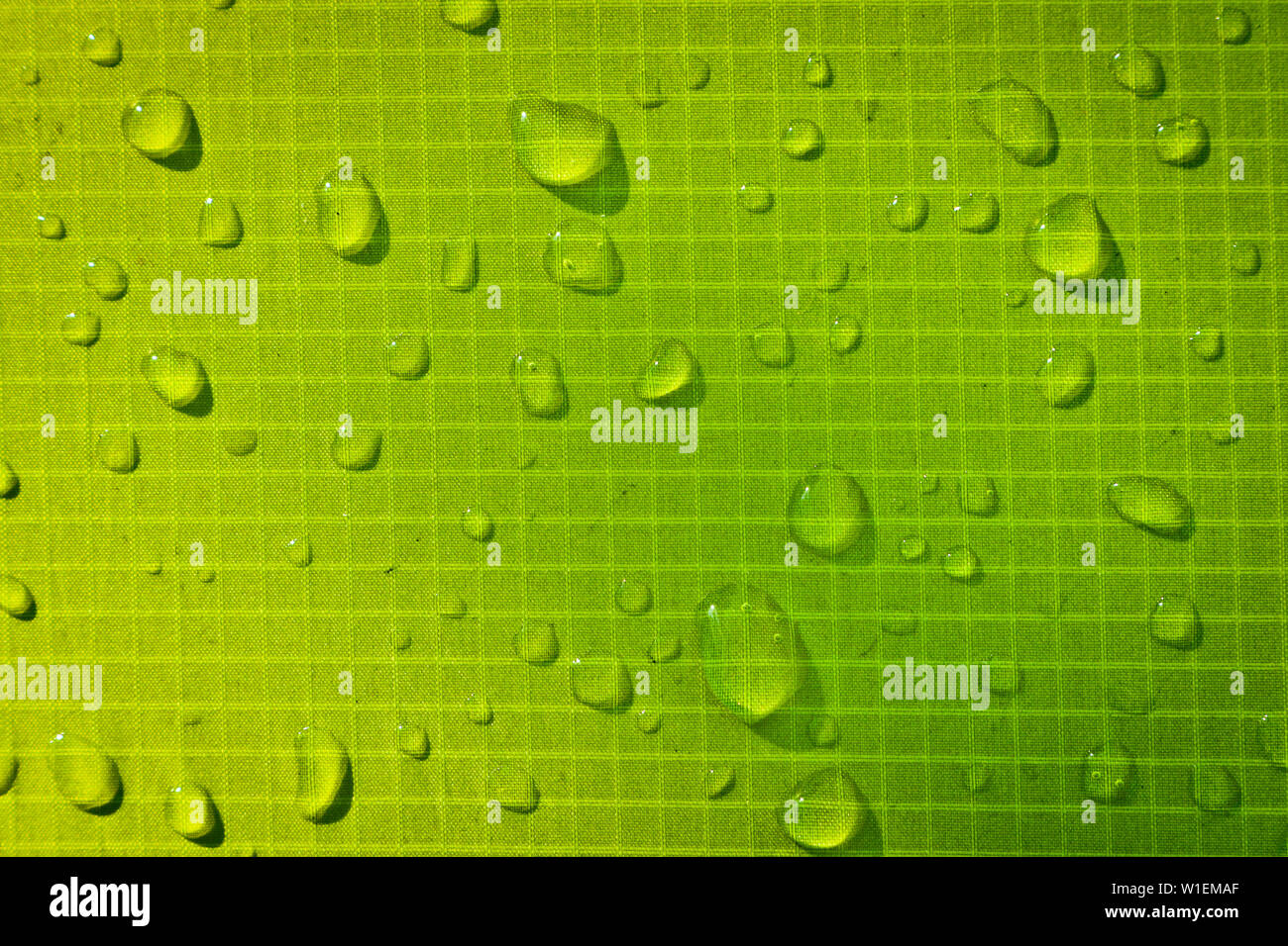 Large drops of water on green textiles with a waterproof effect. Water ...