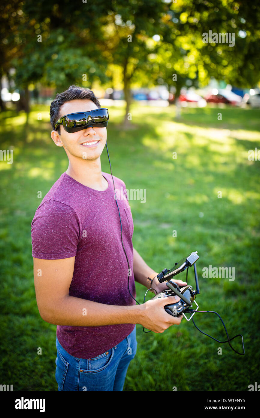 Handsome young man flying a drone outdoors using a VR/augmented reality ...