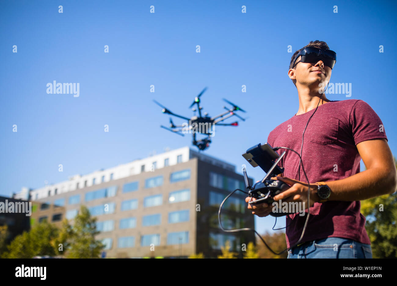 Handsome young man flying a drone outdoors using a VR/augmented reality ...