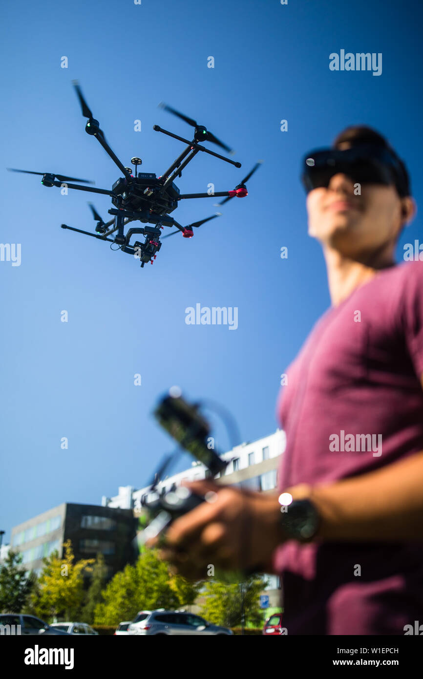 Handsome young man flying a drone outdoors using a VR/augmented reality ...