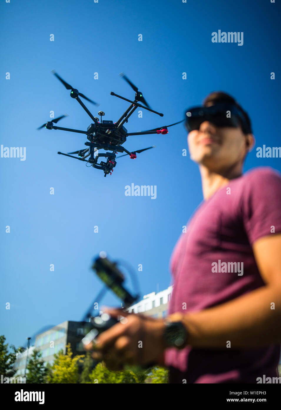 Handsome young man flying a drone outdoors using a VR/augmented reality ...