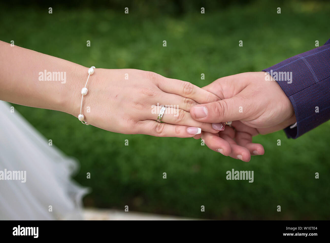Caucasian couple, bride and groom holding hands with visible engagement ...