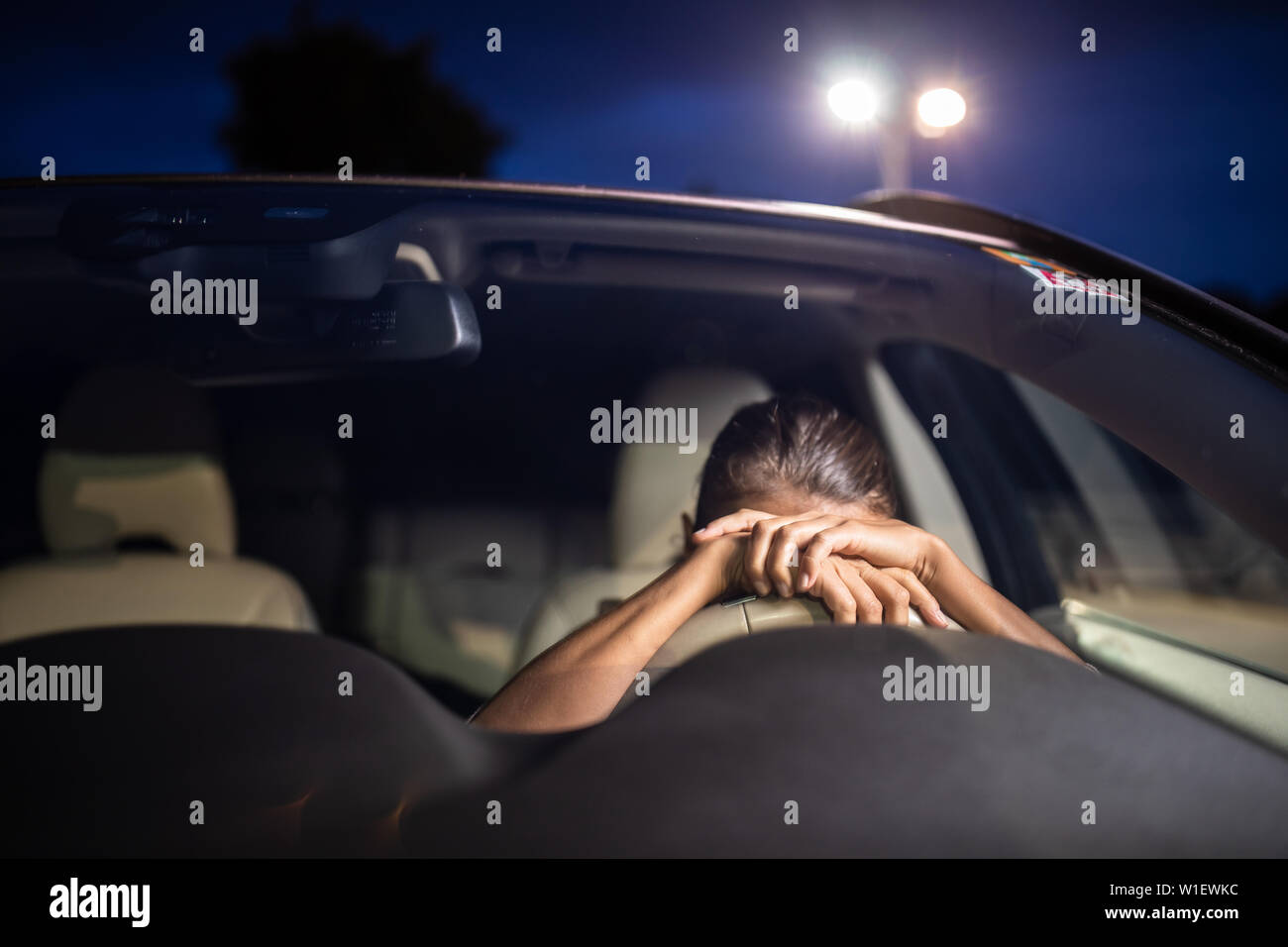 Young female driver at the wheel of her car, super tired, falling ...