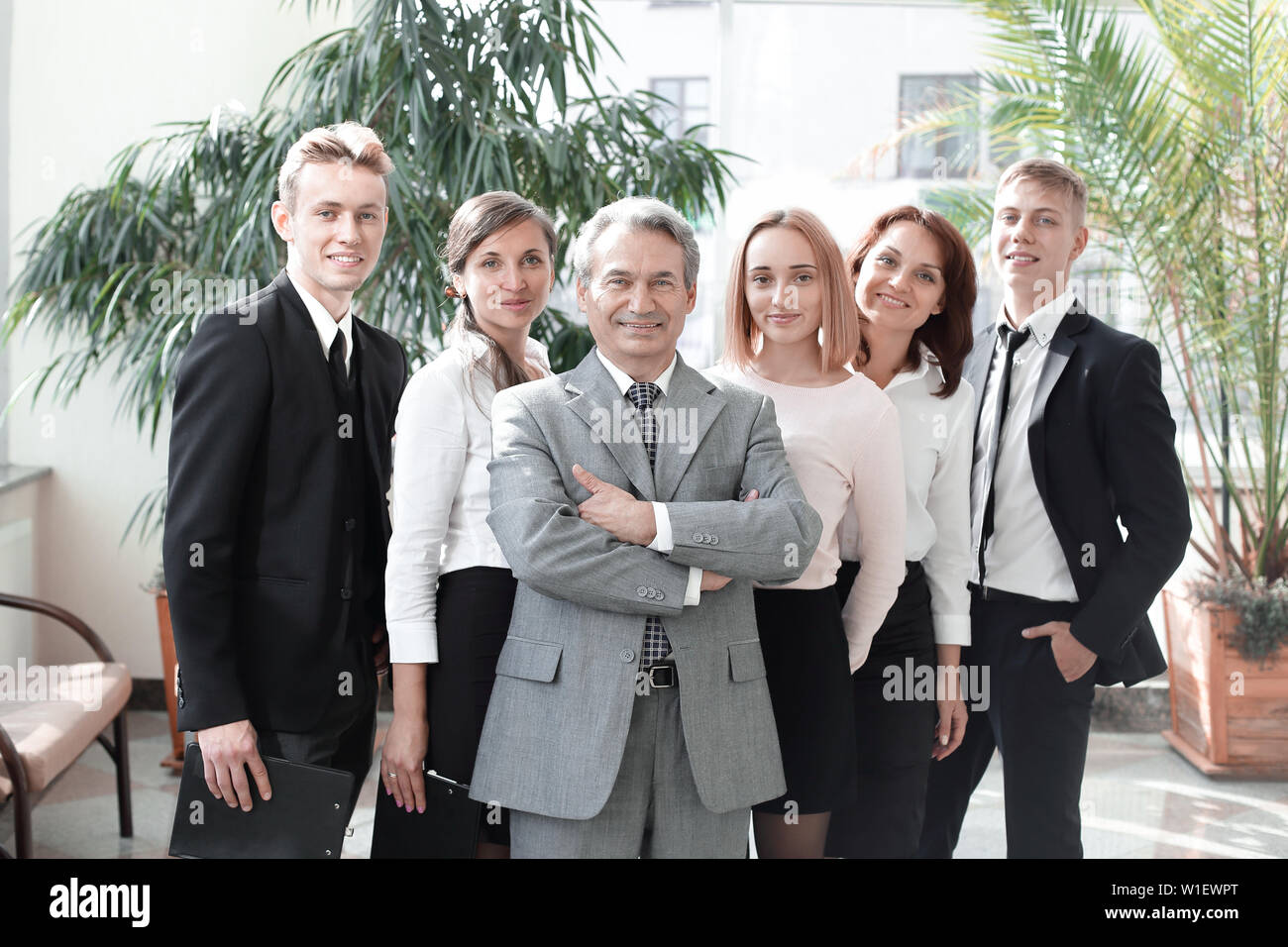 Successful business man standing with his staff in background at office ...