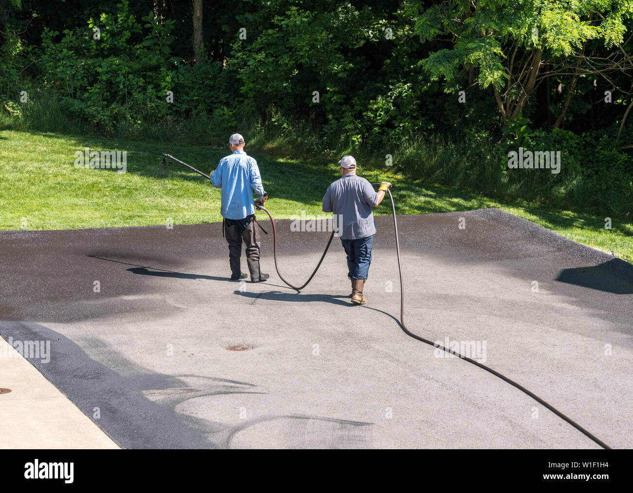 Workers spraying blacktop or asphalt sealer onto roadway Stock Photo ...