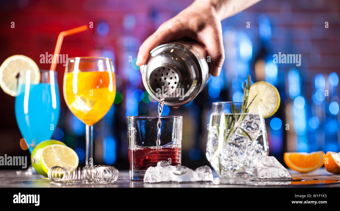 Bartender pouring cocktail into the glass. Set with different cocktails ...