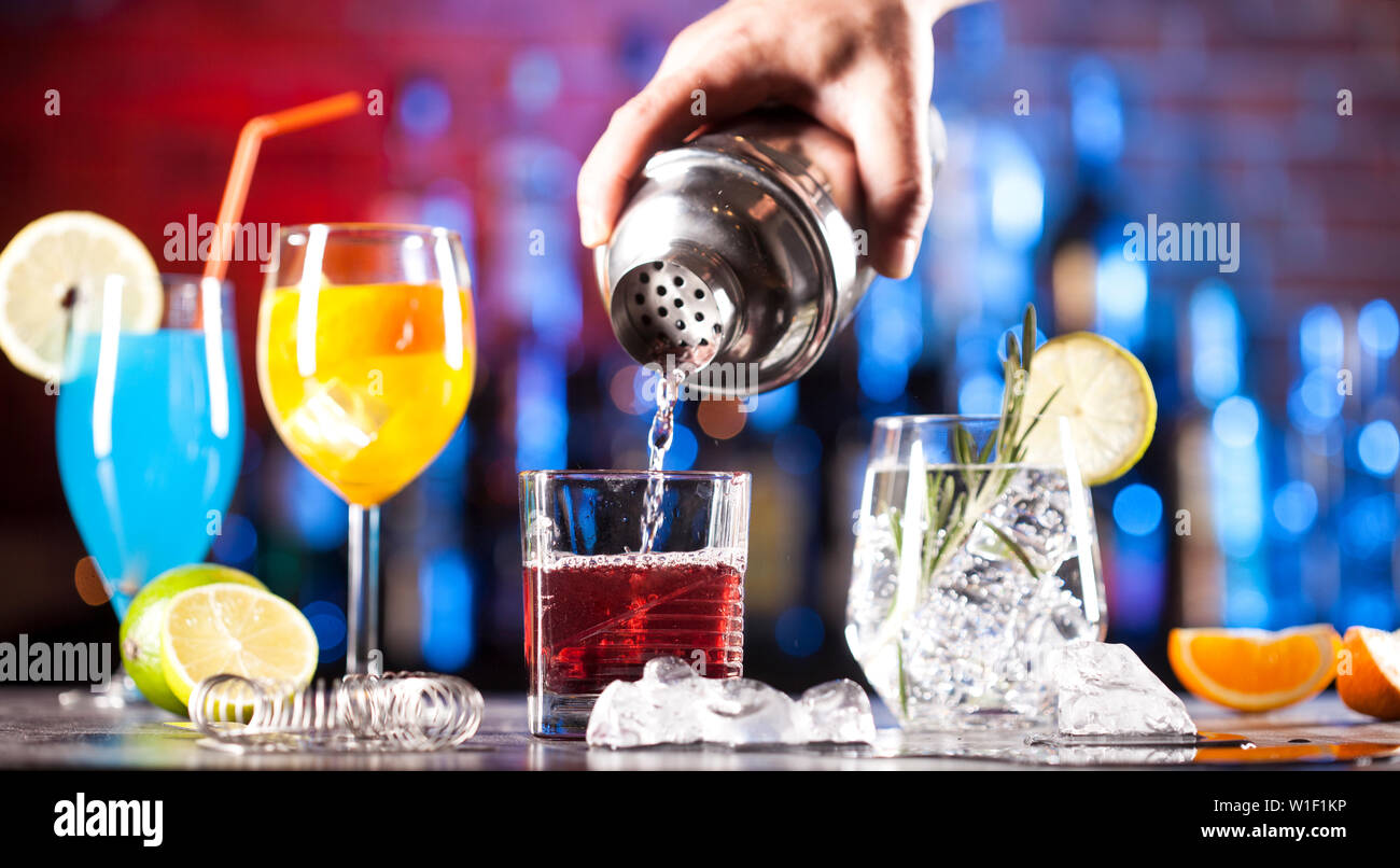 Bartender pouring cocktail into the glass. Set with different cocktails ...
