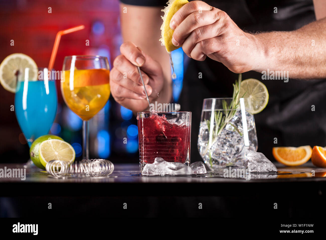 Bartender making cocktail into the glass. Set with different cocktails ...