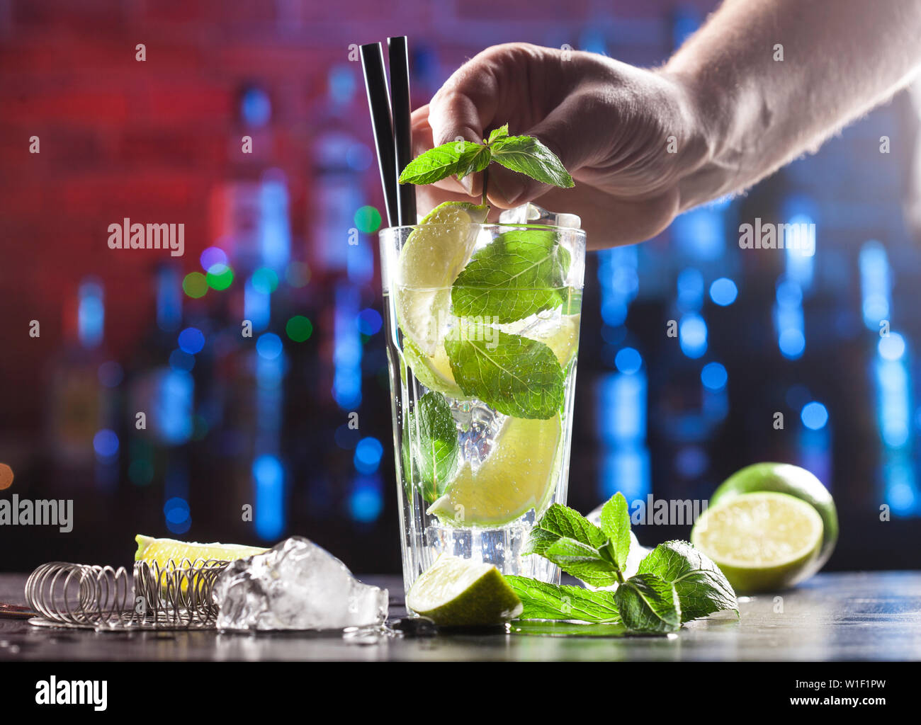 Closeup of barman making a mojito cocktail on bar lights background ...