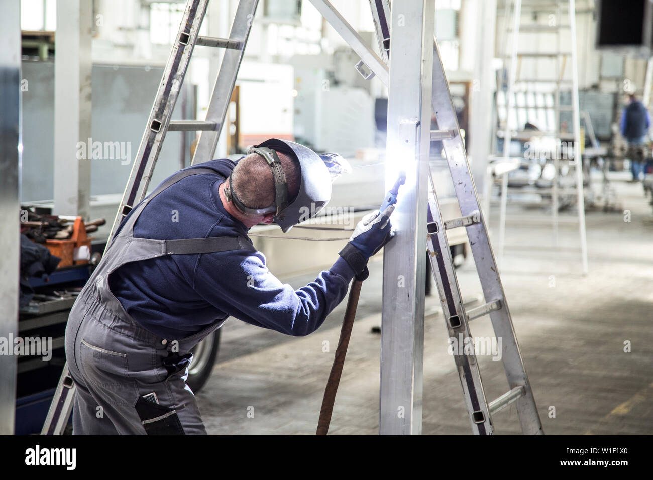 one worker brazing a frame to build something inside a factory Stock ...