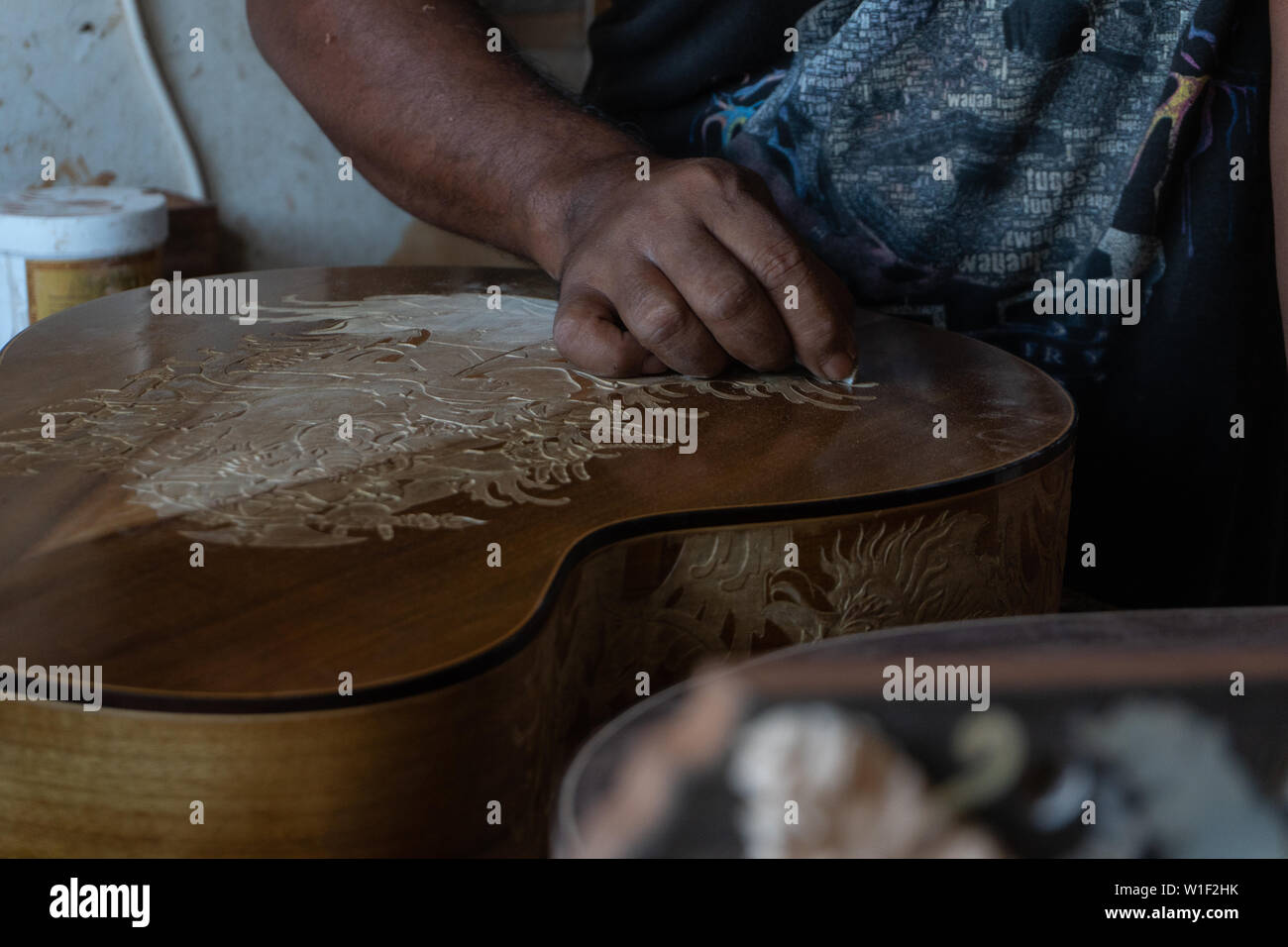 A guitar craftsman are carving a classical guitars made from wood, with ...