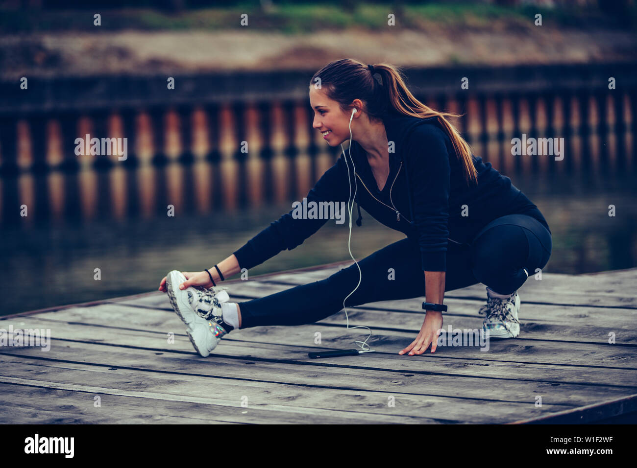 Young beautiful woman doing stretching exercises by the river Stock Photo - Alamy
