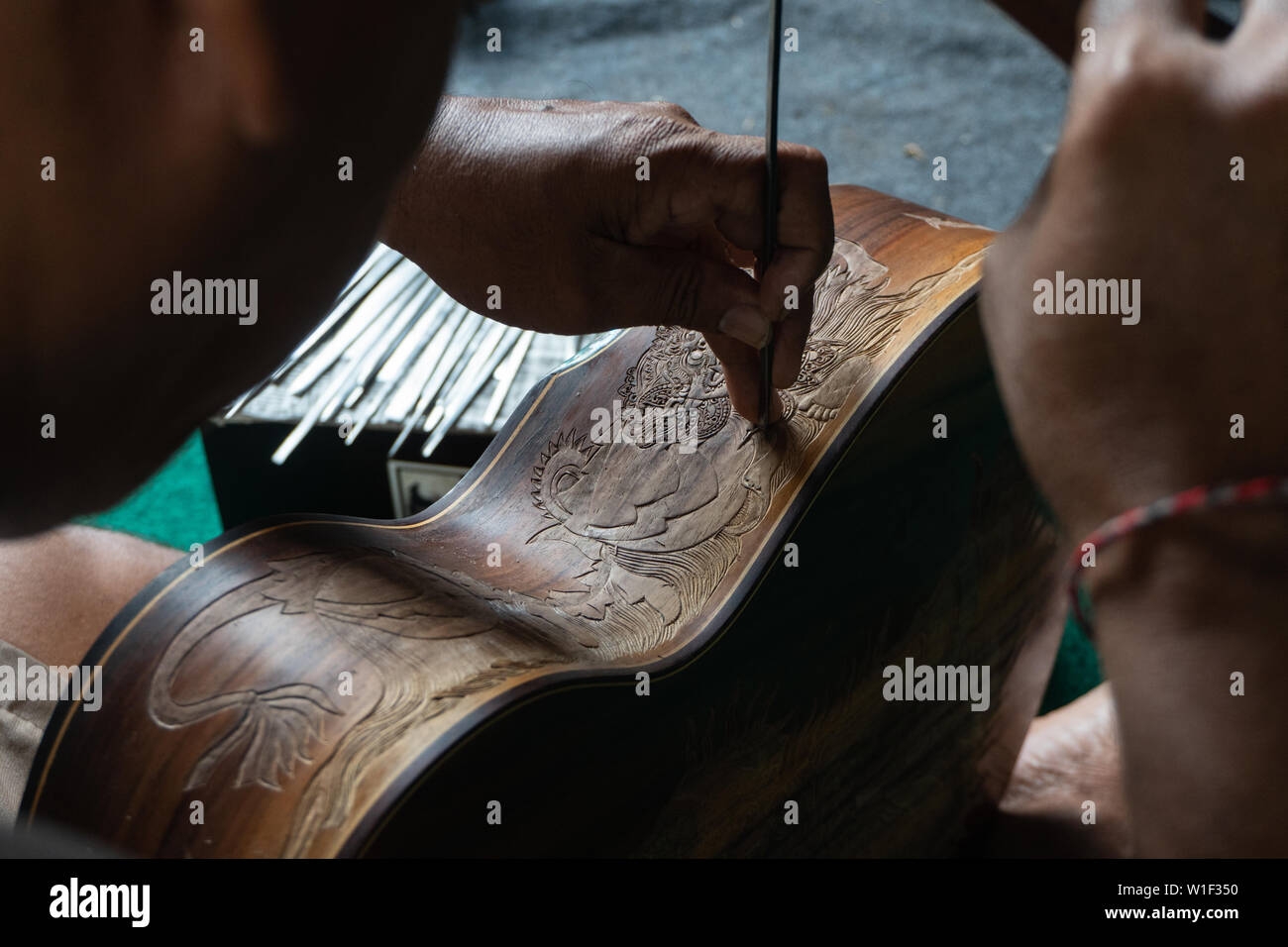 A guitar craftsman are carving a classical guitars made from wood, with ...