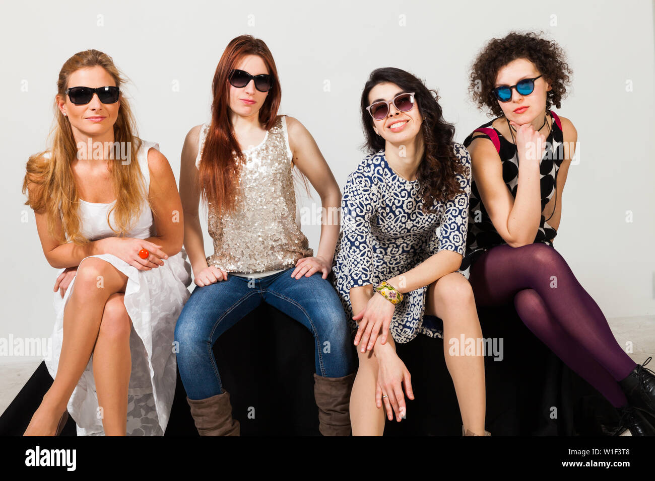 Four beautiful women pose together in the studio, sitting Stock Photo ...